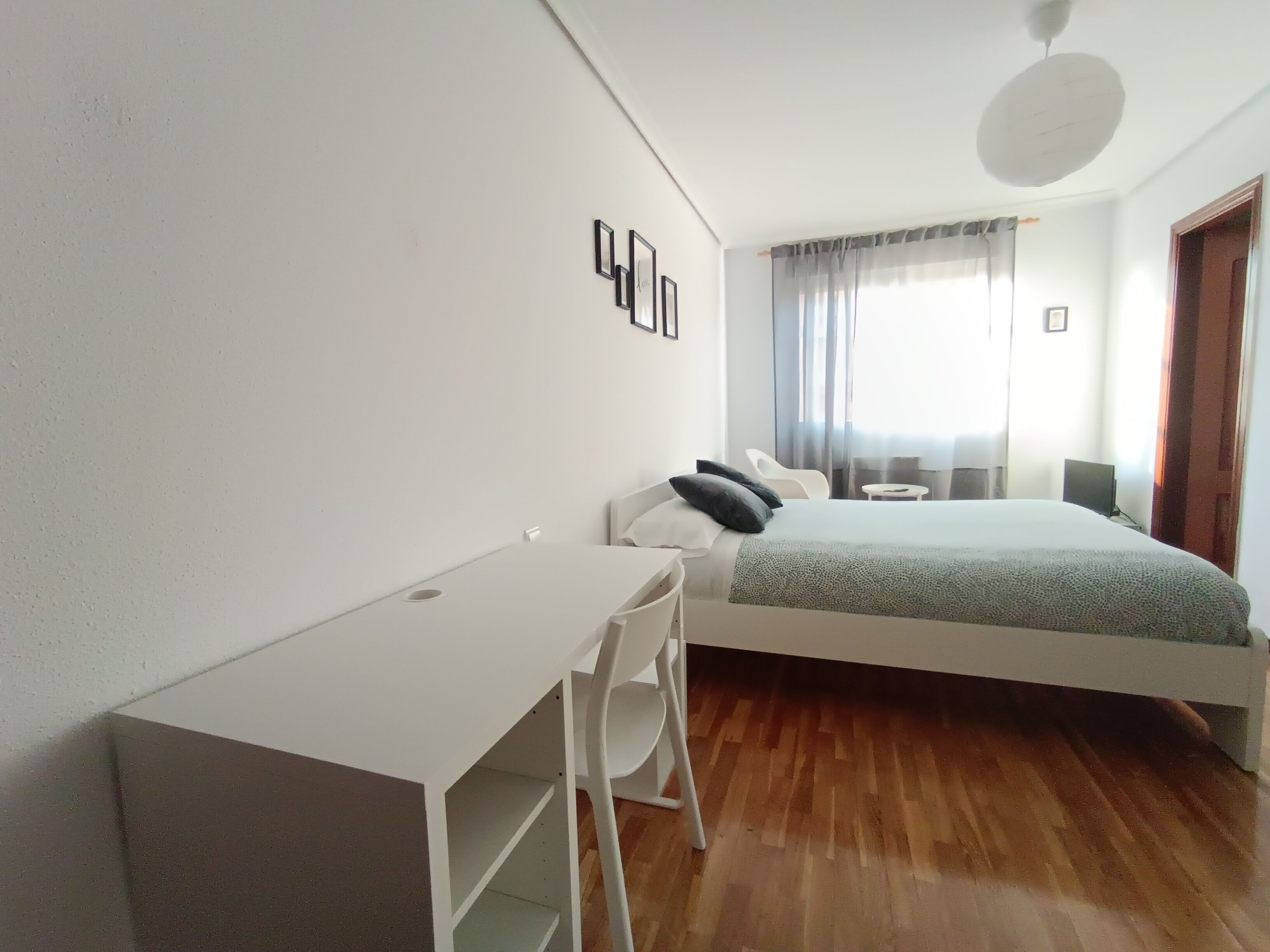 Quarto moderno com cama, escrivaninha e cadeira.