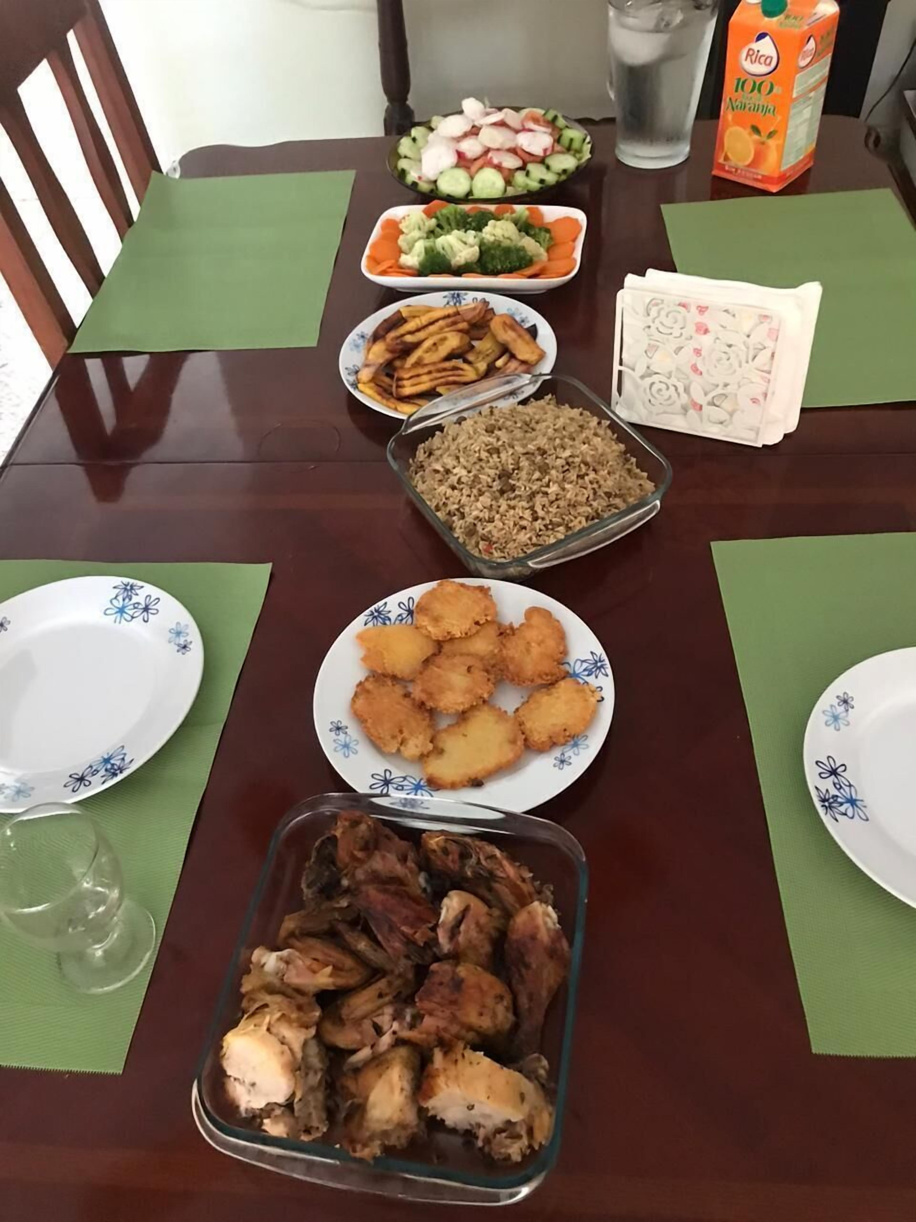 Uma mesa de jantar com diversos pratos, incluindo arroz, frango frito e legumes.