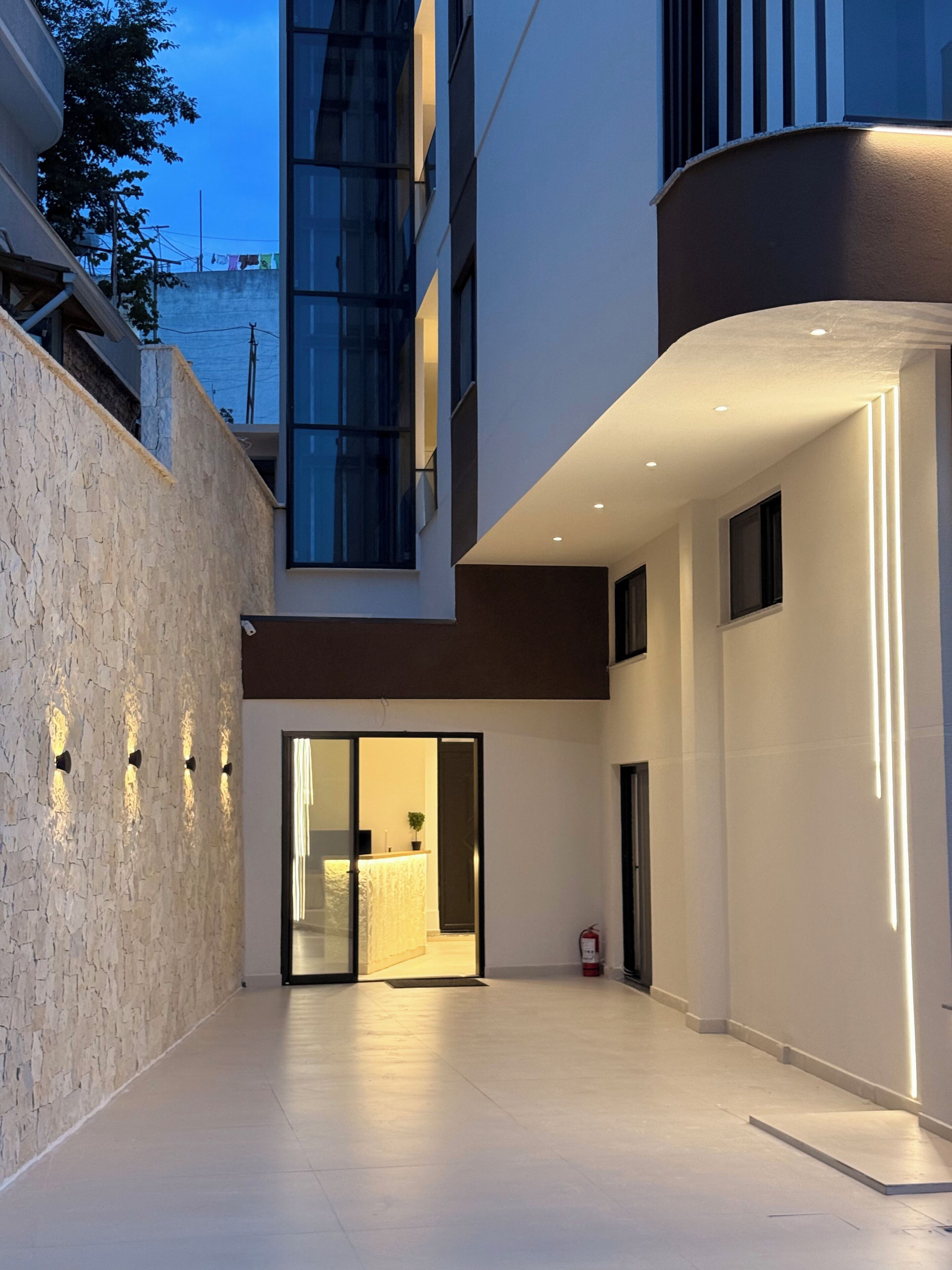 Um edifício moderno com fachada de vidro, parede de pedra e entrada bem iluminada.