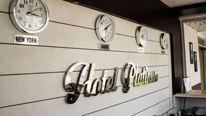 Paredes com relógios mostrando diferentes fusos horários e a placa do Hotel Planetum.