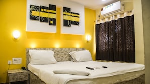 Quarto de hotel com cama, mesa de cabeceira, ar condicionado fixado na parede e decoração na parede.