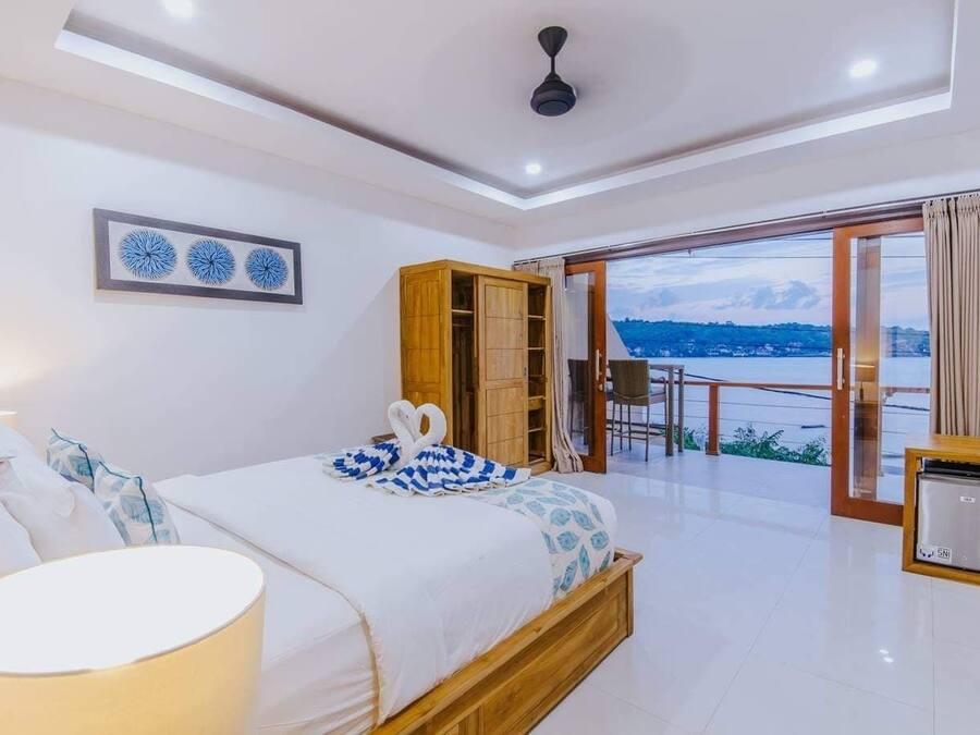 Quarto com cama, escrivaninha e vista para o mar.