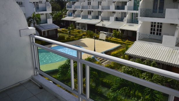 Vista de um resort com vários edifícios brancos, piscina e jardins bem cuidados.