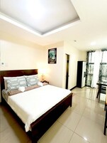 Quarto de hotel com cama, mesa de cabeceira, abajur e um quadro na parede.