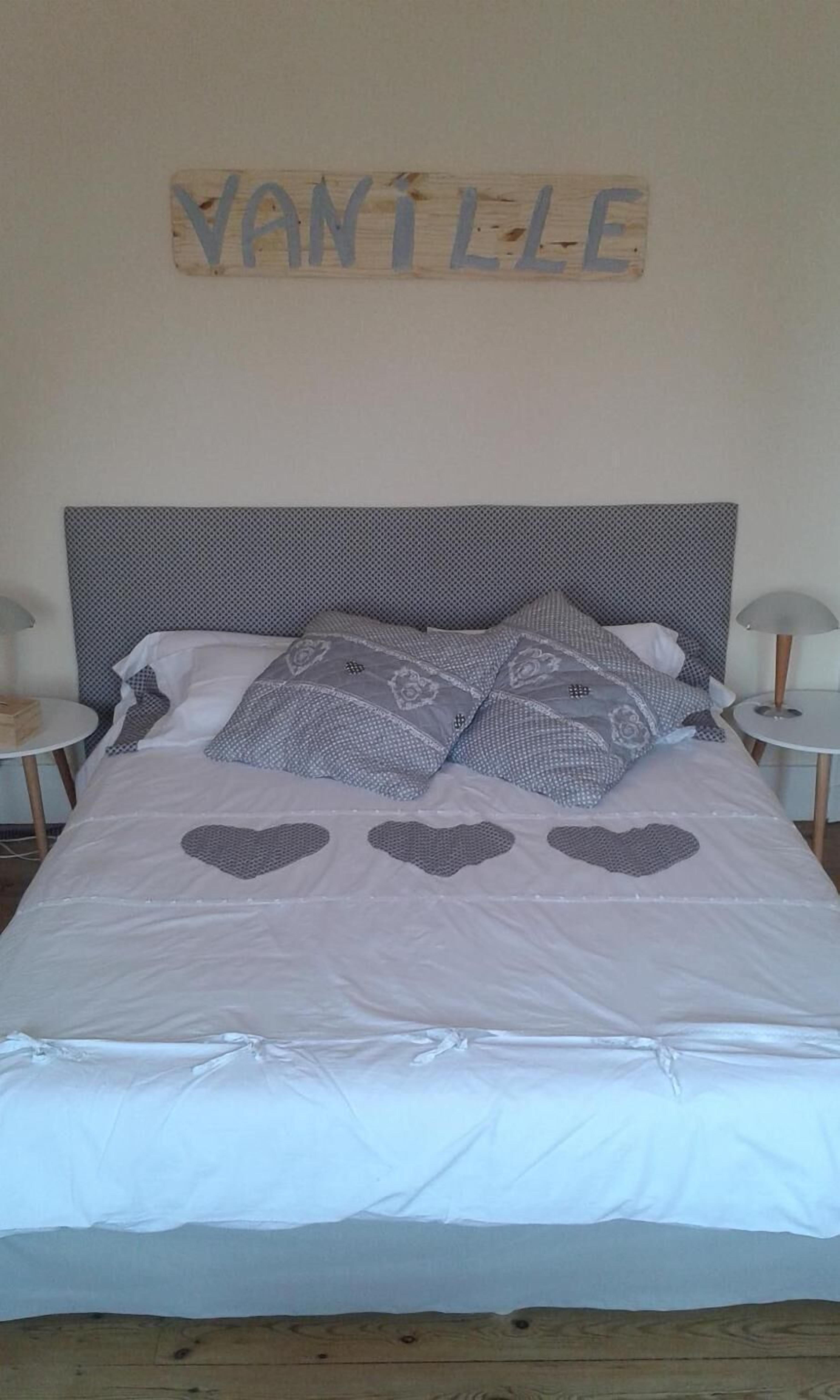Uma cama com cabeceira, travesseiros e cobertor.