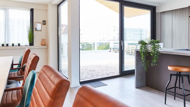 Interior moderno com área de jantar, bar e porta de vidro deslizante que dá para um pátio externo.