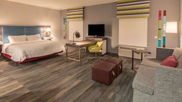 Quarto de hotel com cama, escrivaninha, poltrona e sofá.