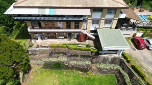 Um edifício de vários andares com piscina, um alpendre coberto e um jardim bem cuidado.