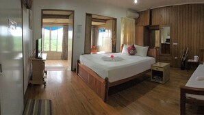 Quarto com uma cama grande, uma mesinha de cabeceira, um guarda-roupa de madeira e uma janela com cortinas.