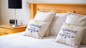 Cama bem arrumada com duas almofadas com a etiqueta "Inglewood Guesthouse".