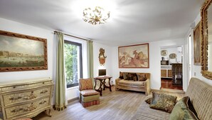 Uma sala de estar ampla com uma pintura grande, um sofá, uma poltrona e um armário de madeira.