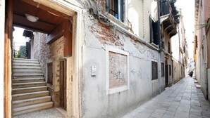 Uma rua estreita na cidade, com uma escadaria que leva à entrada de um edifício.