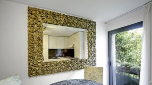 Quarto com cama de mármore, um espelho grande e ornamentado, e vista para o verde através de uma porta de vidro deslizante.