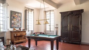 Quarto com mesa de bilhar, um armário de madeira, uma grande obra de arte emoldurada e um guarda-roupa de madeira escura.