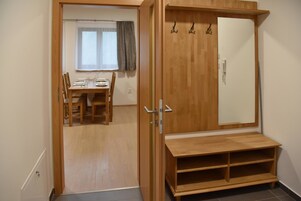 Quarto com guarda-roupa de madeira, mesa de jantar com cadeiras e janela com cortinas.