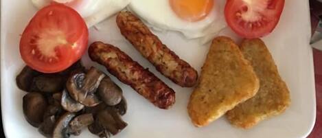 Prato de café da manhã com bacon, ovos, linguiça, cogumelos, tomate, feijão e torradas.