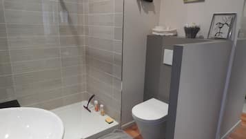Uma casa de banho moderna com banheira, sanita e chuveiro.