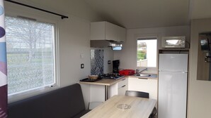 Uma cozinha compacta equipada com fogão a gás, micro-ondas e frigorífico.