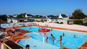 Uma área de piscina com várias piscinas, espreguiçadeiras e um boi de água vermelho inflável.