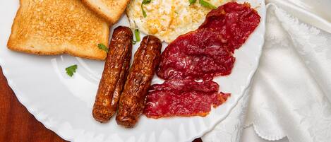 Um prato com torradas, linguiça e ovos mexidos sobre uma mesa de madeira.