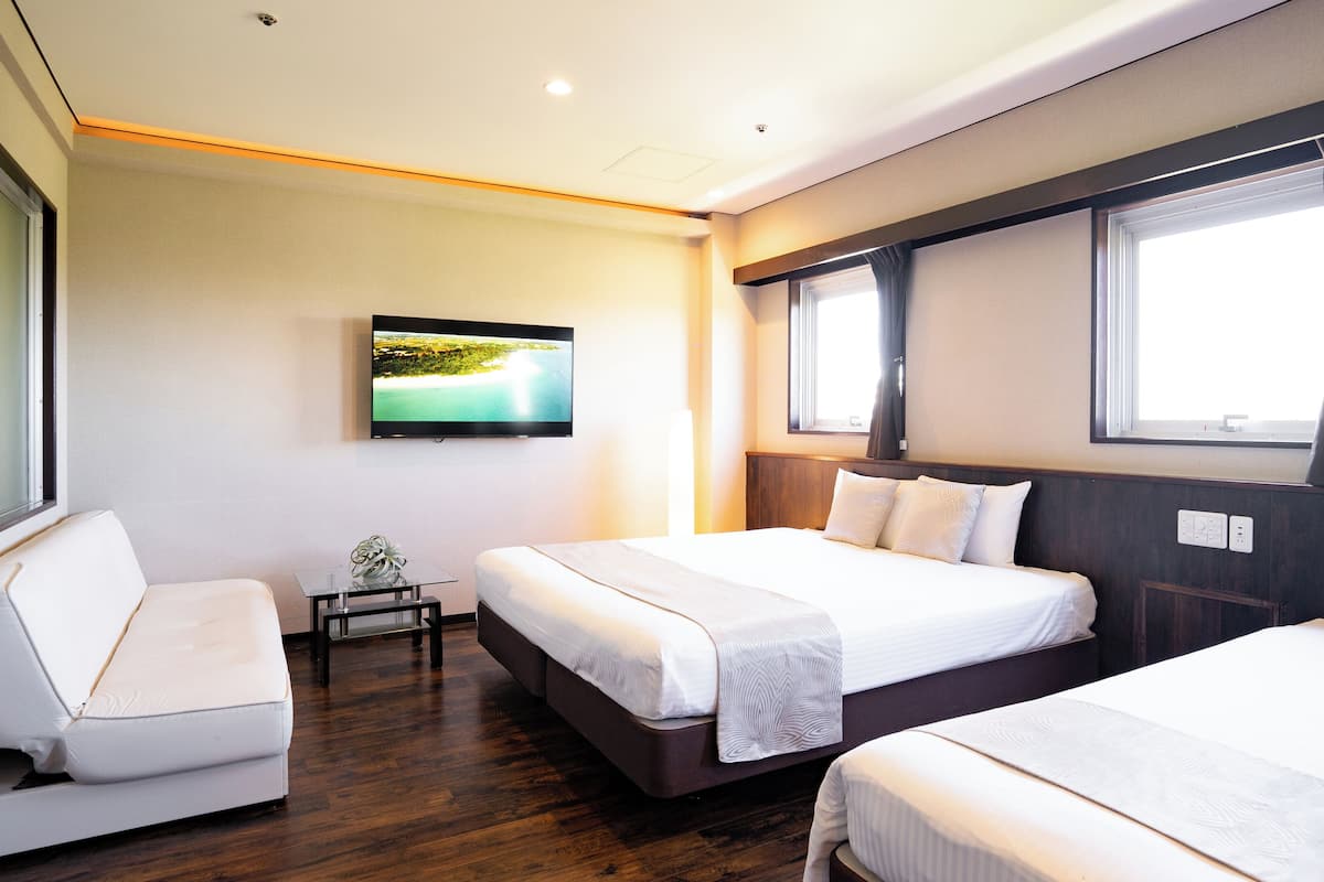 Quarto de hotel com duas camas, televisão na parede e janela com cortinas.