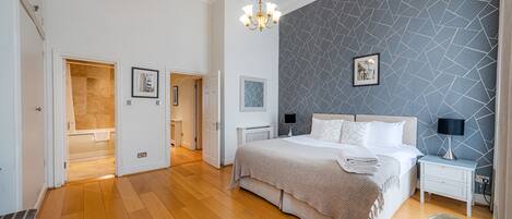 Um quarto espaçoso com uma cama grande, uma mesa de cabeceira e um candelabro.
