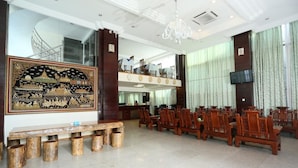 Um hall amplo com uma grande parede decorativa, mobiliário de madeira e um lustre.