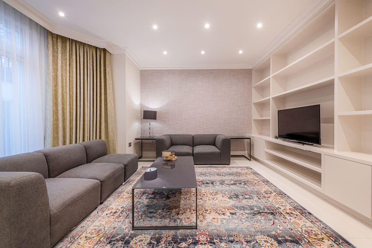 Uma sala de estar moderna com sofá, mesa de centro, TV de tela plana e estantes embutidas.