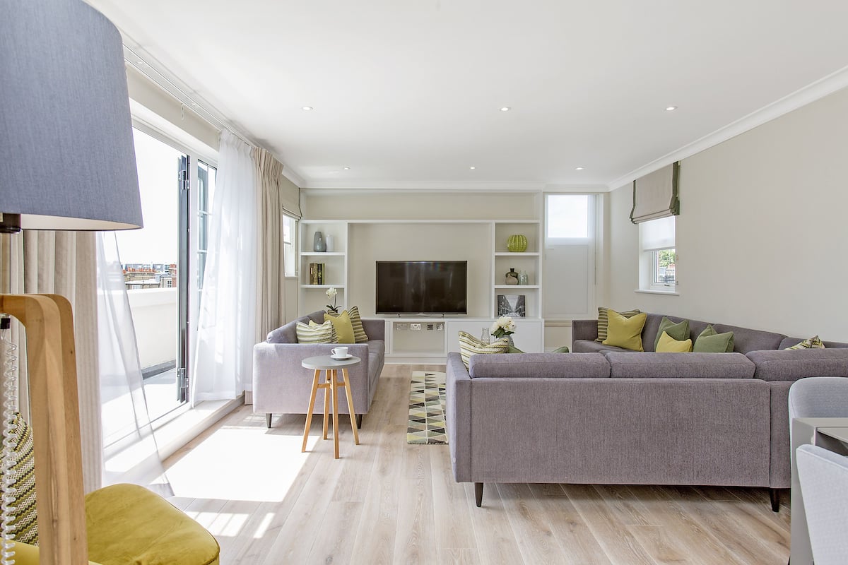 Uma sala de estar moderna com um sofá, uma televisão e uma mesa pequena.