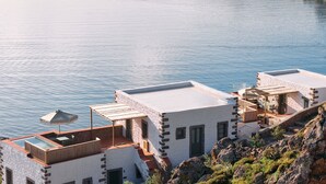 Um edifício à beira-mar com terraço no telhado, piscina e vista para o mar.