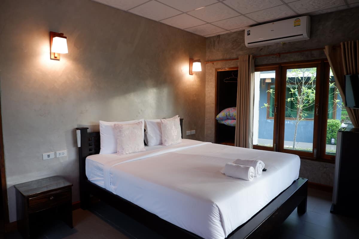 Quarto de hotel com cama grande, luminárias de cabeceira, ar condicionado e vista pela janela.