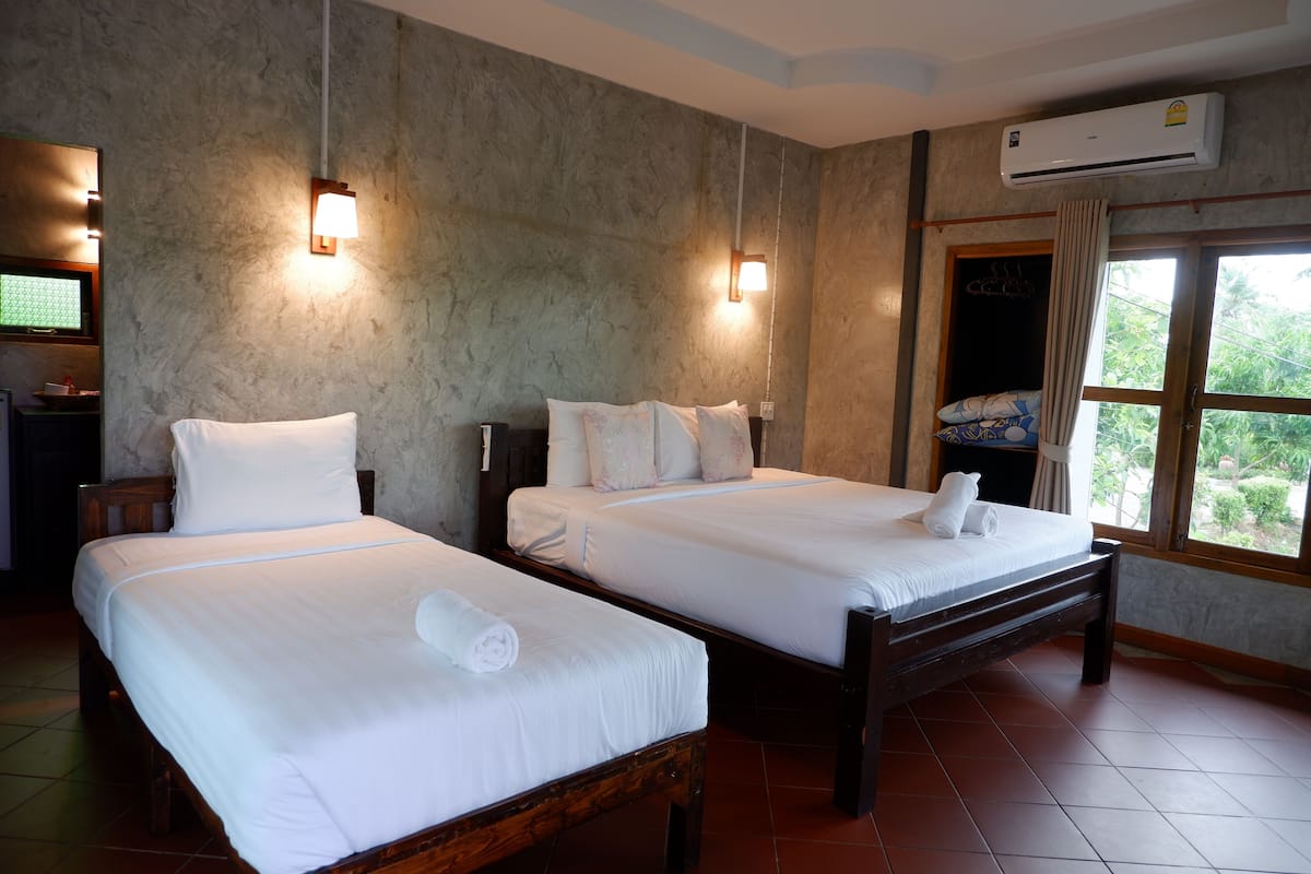 Quarto de hotel com duas camas, televisão e janela com vista.
