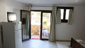 Uma cozinha compacta com geladeira, uma mesa pequena e um banco.