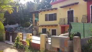 Um edifício amarelo com telhado vermelho, parede de pedra e portão de metal.