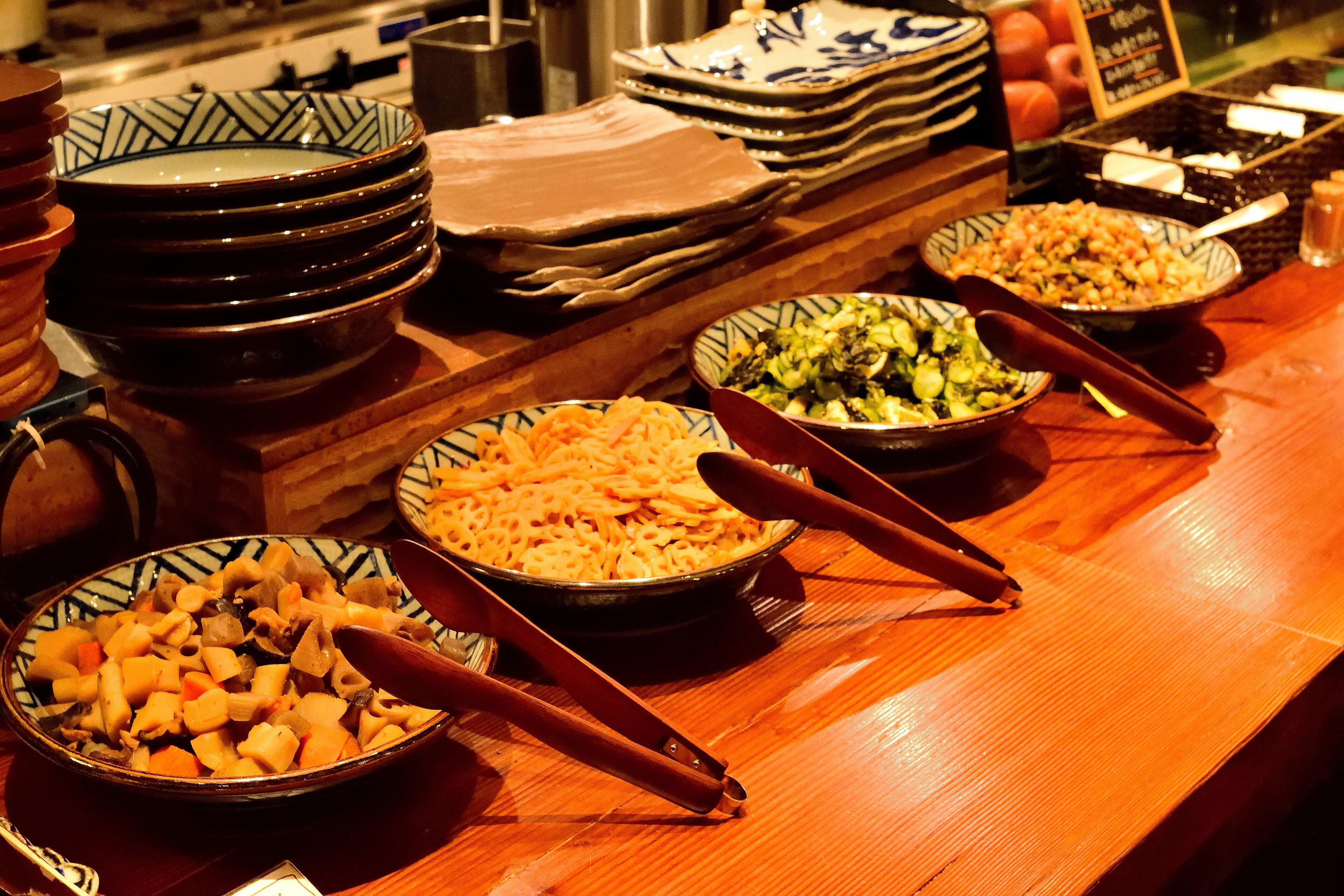Mesa de buffet com diversos pratos e utensílios de servir.