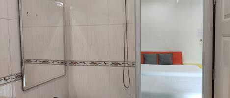 Casa de banho com lavatório, espelho e área de duche com porta de vidro.