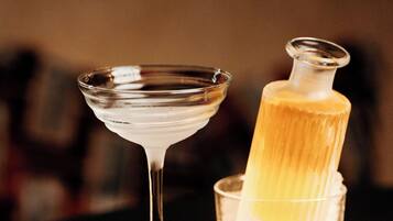 Uma taça de martini e uma garrafa de bebida sobre um balcão de bar.
