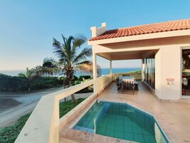 Um edifício moderno com piscina, área de estar externa e vista para o oceano.