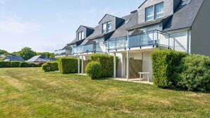 Uma fileira de casas modernas com varandas, sebes bem aparadas e gramado bem cuidado.