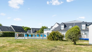 Zona residencial com casas modernas, céu claro e gramado.