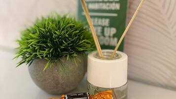 Uma pequena planta em vaso, um recipiente de vidro com duas bengalas de madeira e vários chocolates embalados.