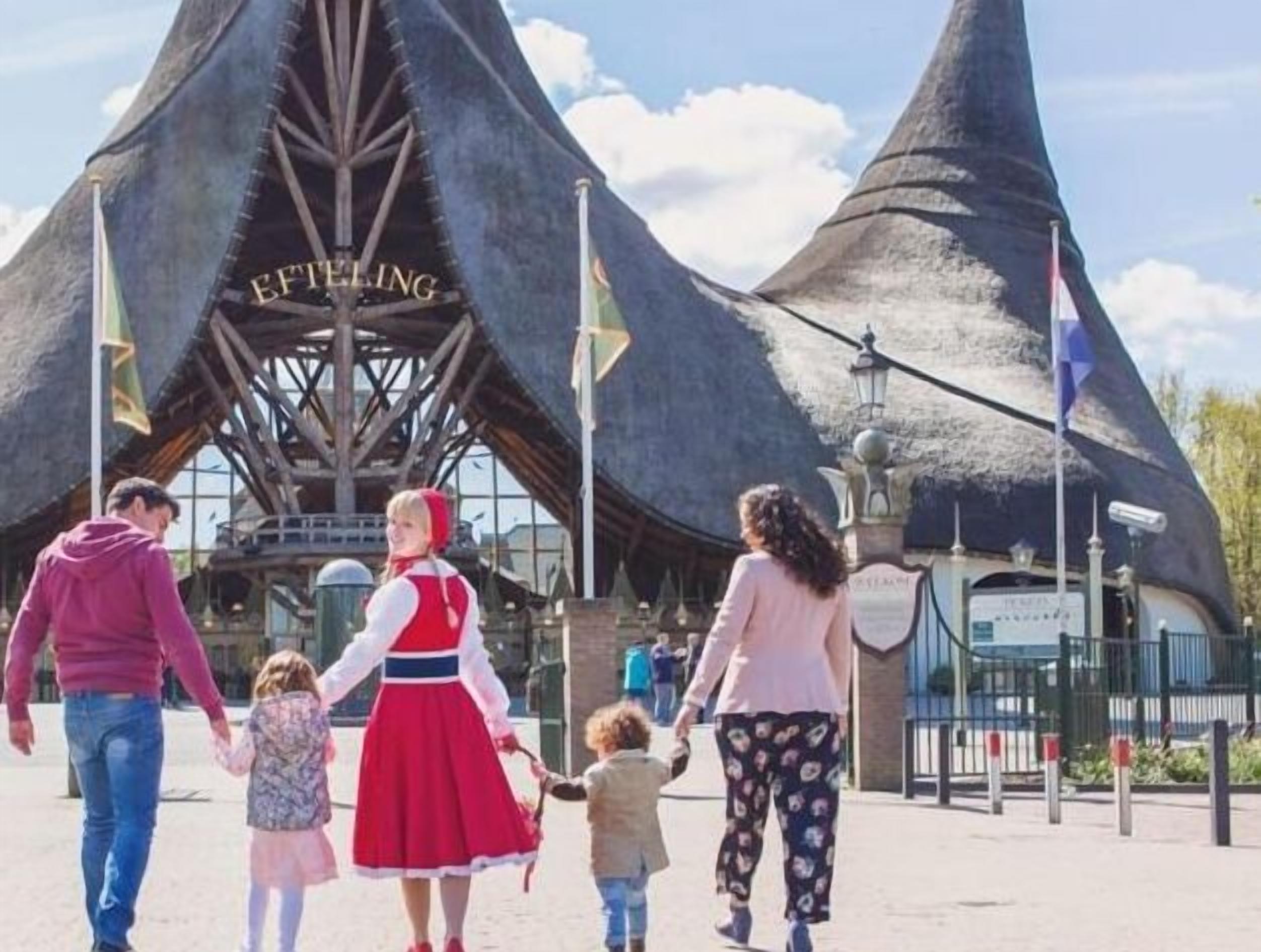 Uma família caminhando em direção a um edifício com um telhado cônico característico e a palavra "EFTELING" visível na entrada.