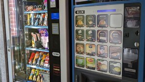 Máquina de vendas com diversas opções de comida e bebida, incluindo lanches, refrigerantes e café.