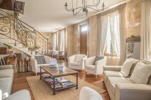 Uma sala de estar ampla com escada, mobiliário branco e lareira.