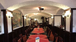 Restaurante com uma mesa comprida, cadeiras e uma tela de projeção.
