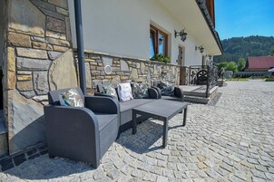 Um edifício de paredes de pedra com área externa para sentar e um pátio pavimentado.