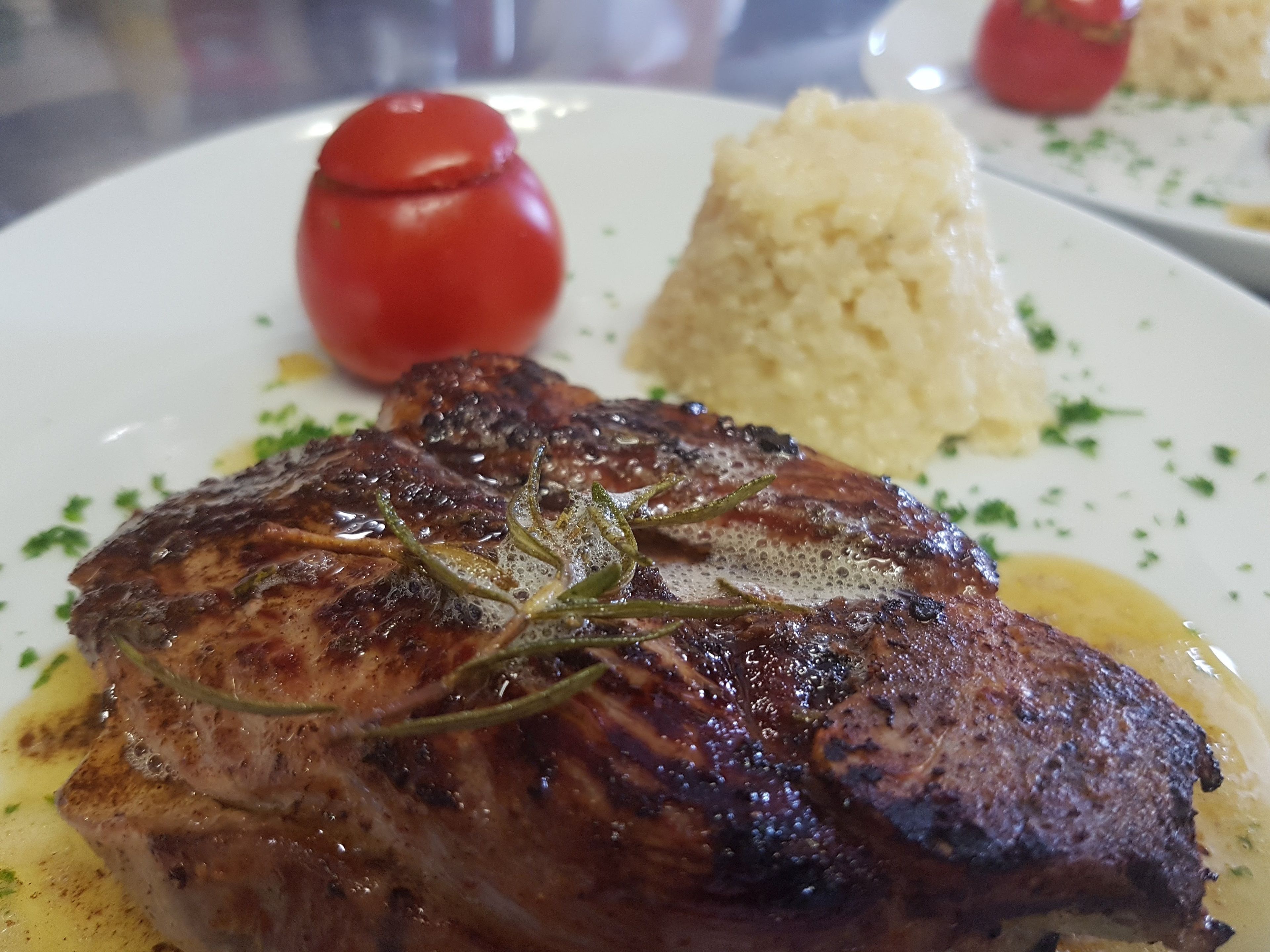 Bife com acompanhamento, tomate e purê de batatas no prato.