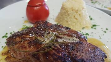 Bife com acompanhamento, tomate e purê de batatas no prato.