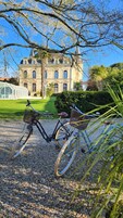 Uma bicicleta estacionada em um caminho de cascalho, com um edifício grande e histórico ao fundo.