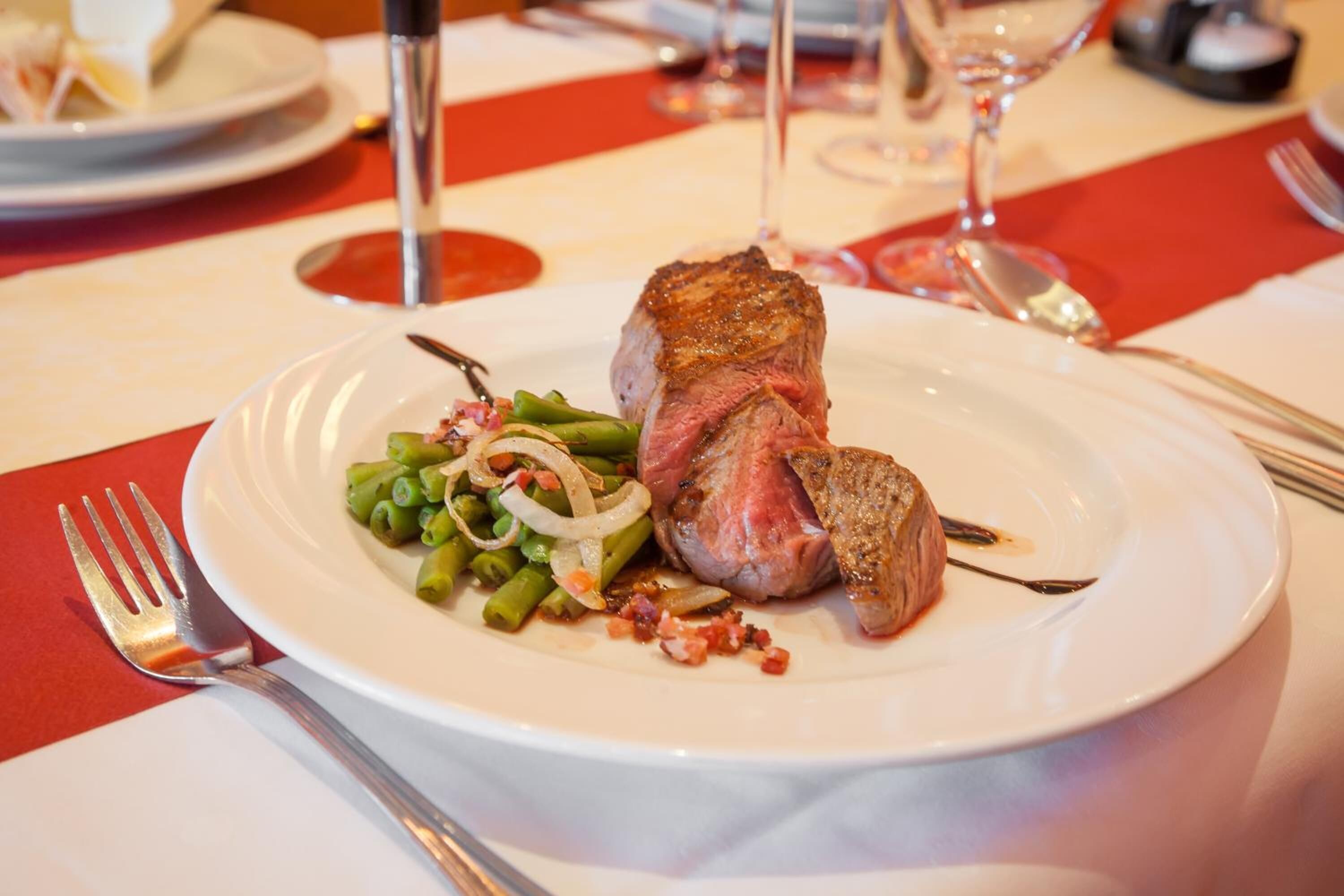 Um prato com bife, vagem e cebola.
